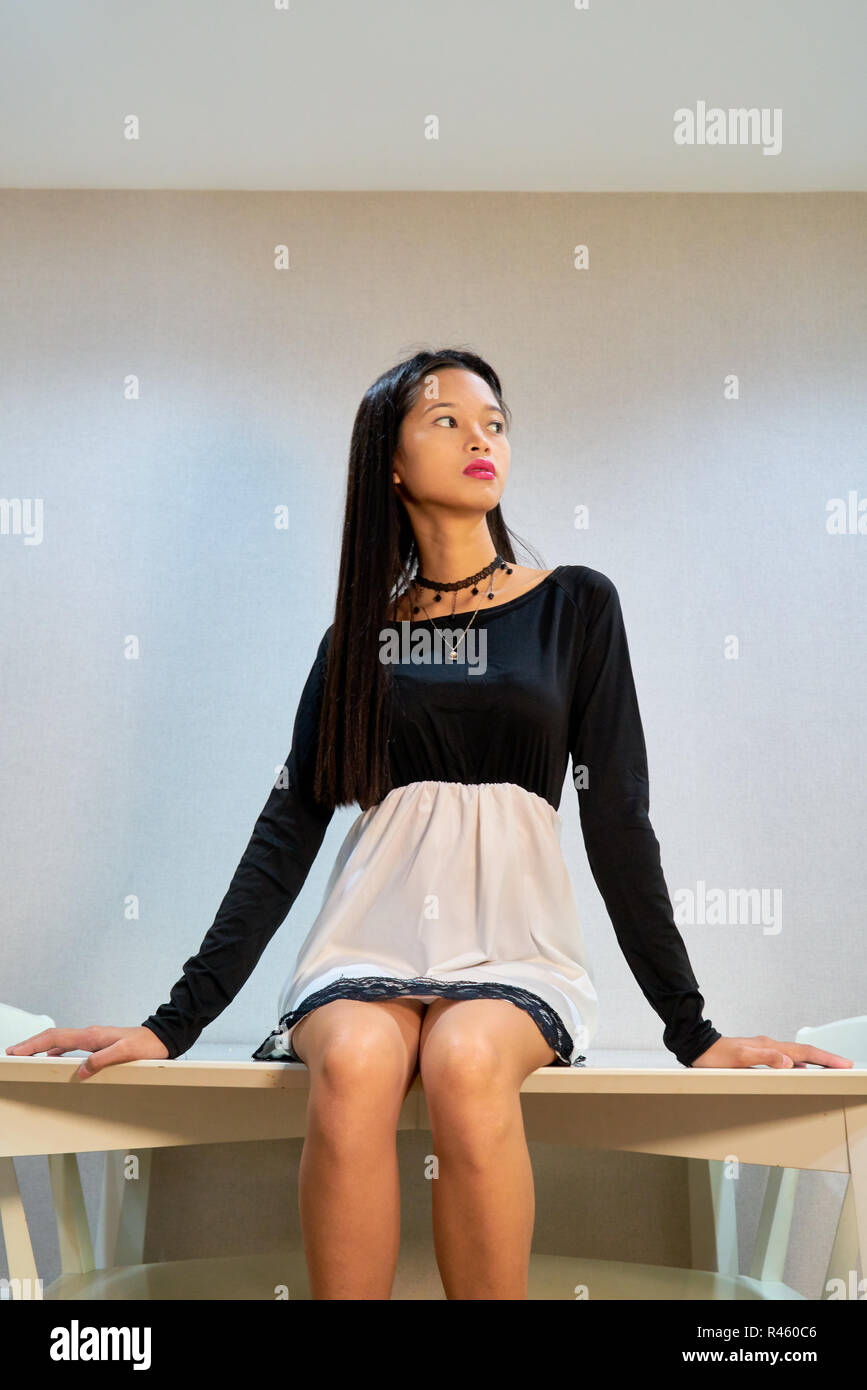Beautiful woman posing - sitting on table, thinking, looking away Stock ...