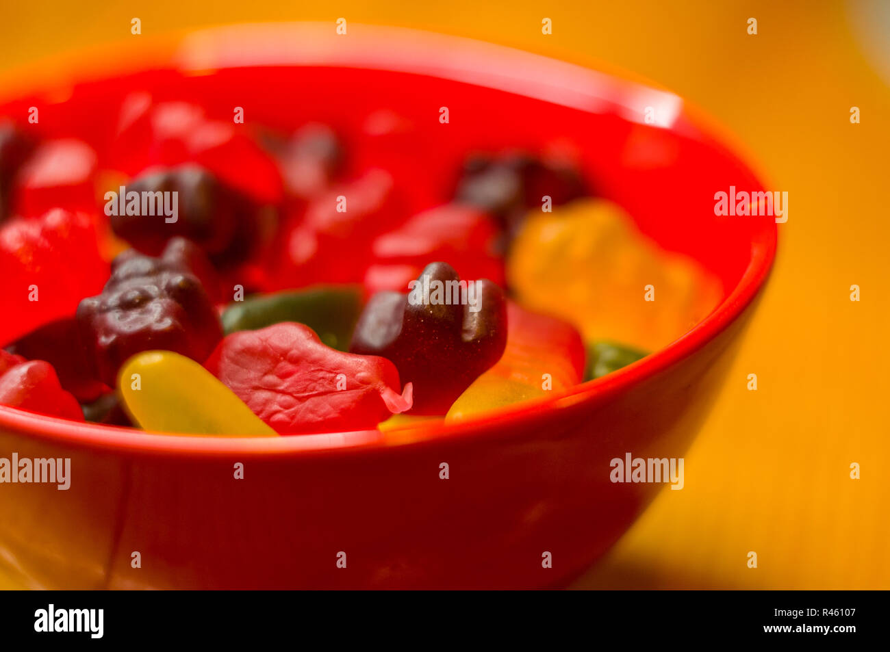 still life - a translucent multi-colored jelly sweeties in red bowl ...