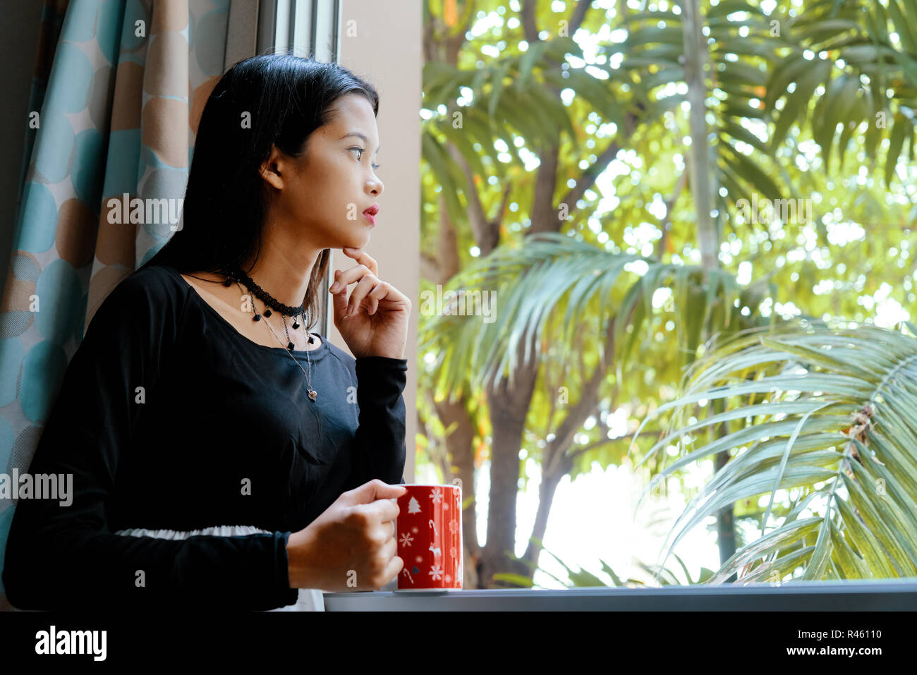 Beautiful woman posing - thinking, holding a cup, alone Stock Photo - Alamy
