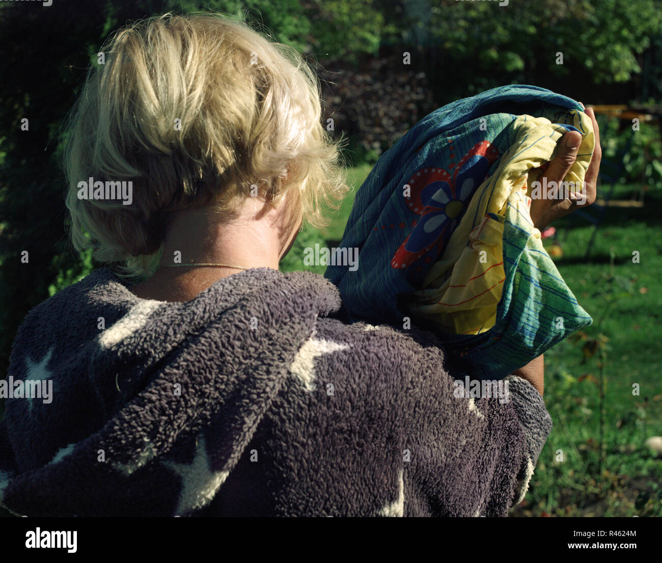 A woman carrying just washed laundry outdoors sunny day cropped shot ...