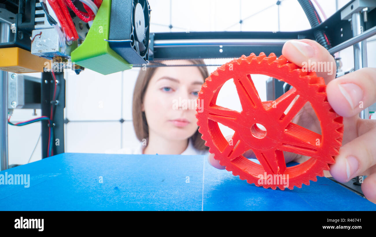 Young women designer in 3d printing lab. Girl takes the finished detail ...