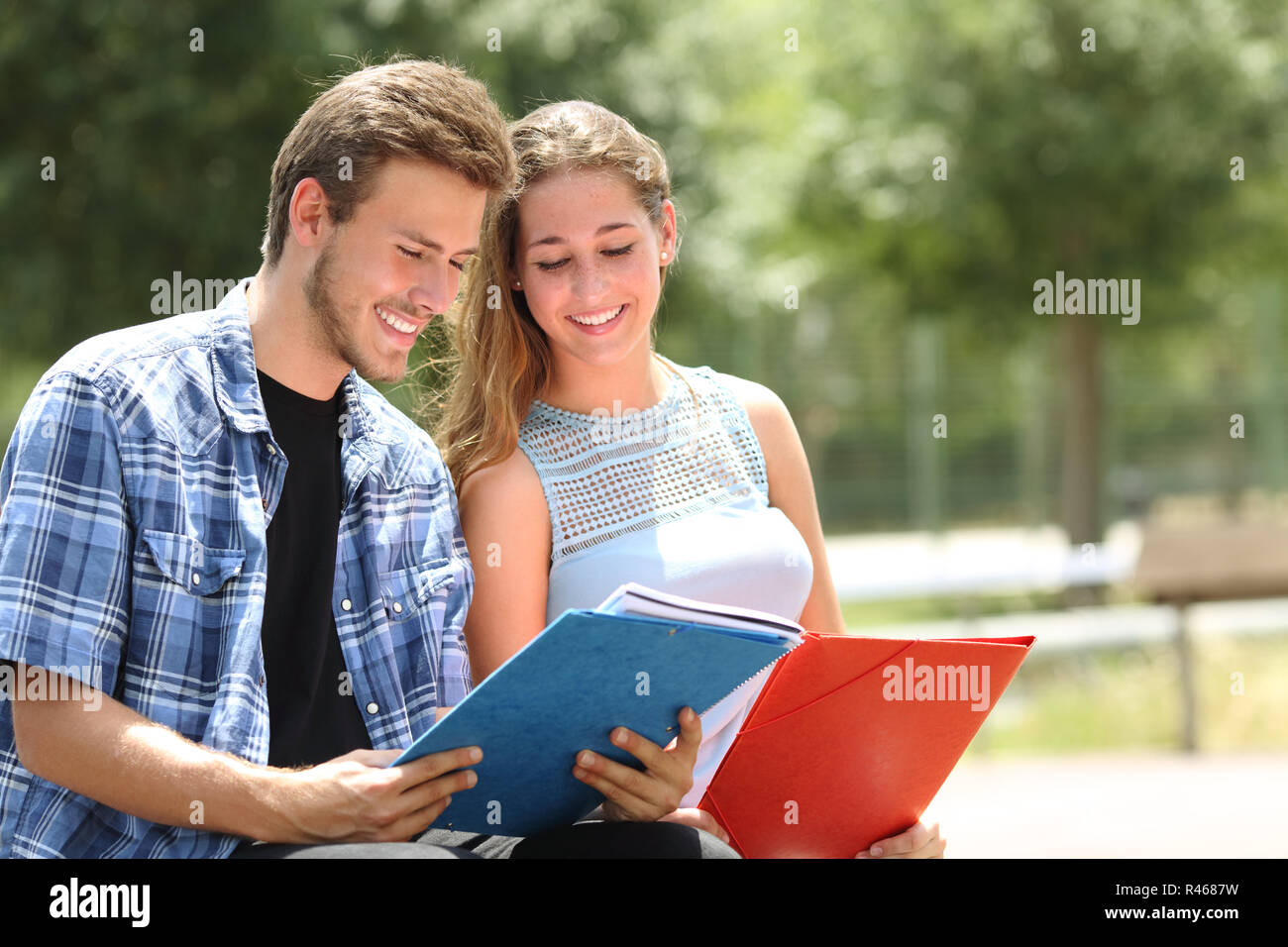 Couple of happy students studying together sitting in a campus Stock ...