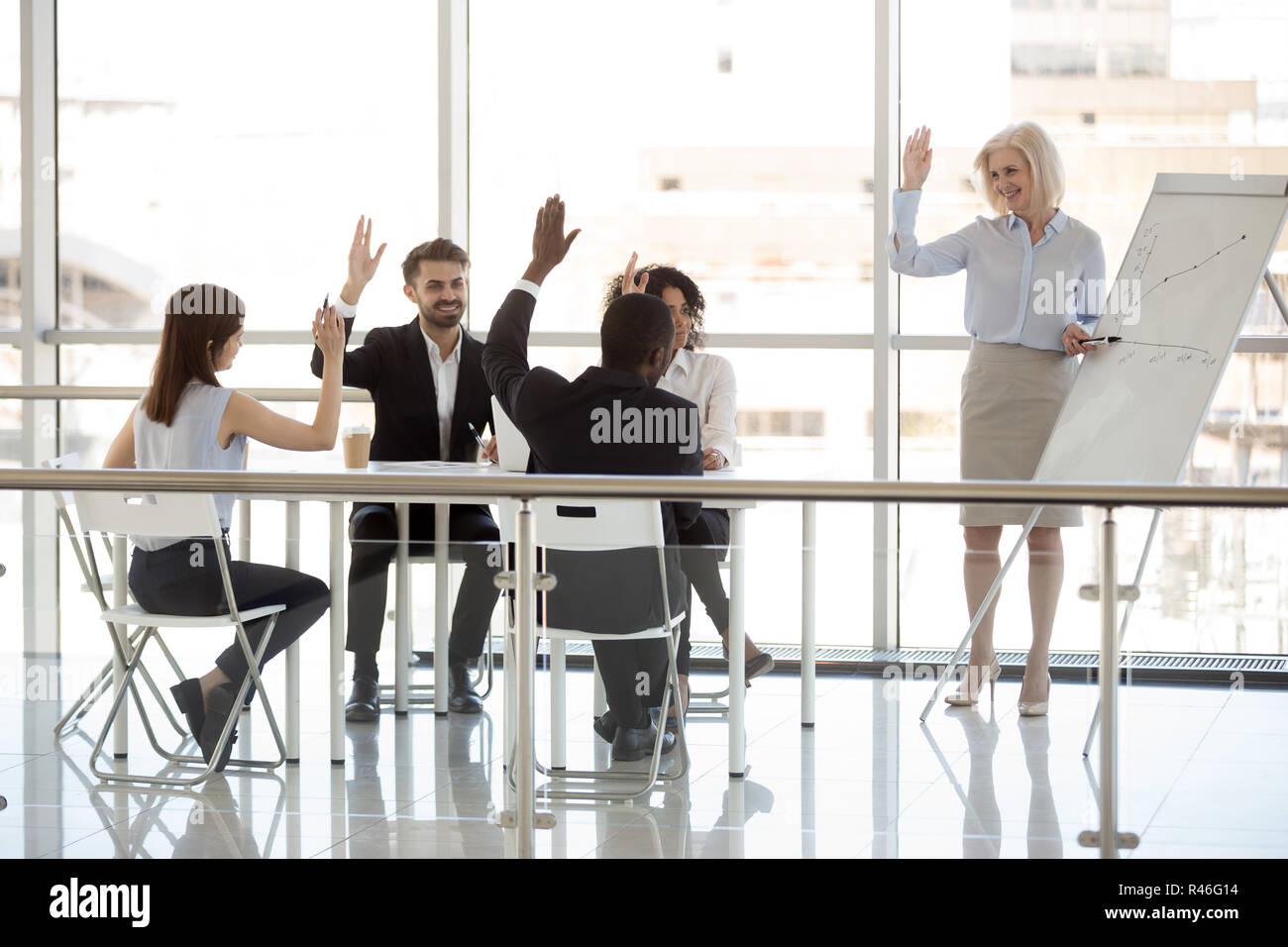 Happy diverse businesspeople and coach raising hands at office t Stock ...