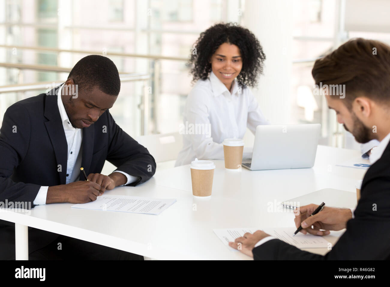 African american and caucasian businessmen signing contracts con Stock ...