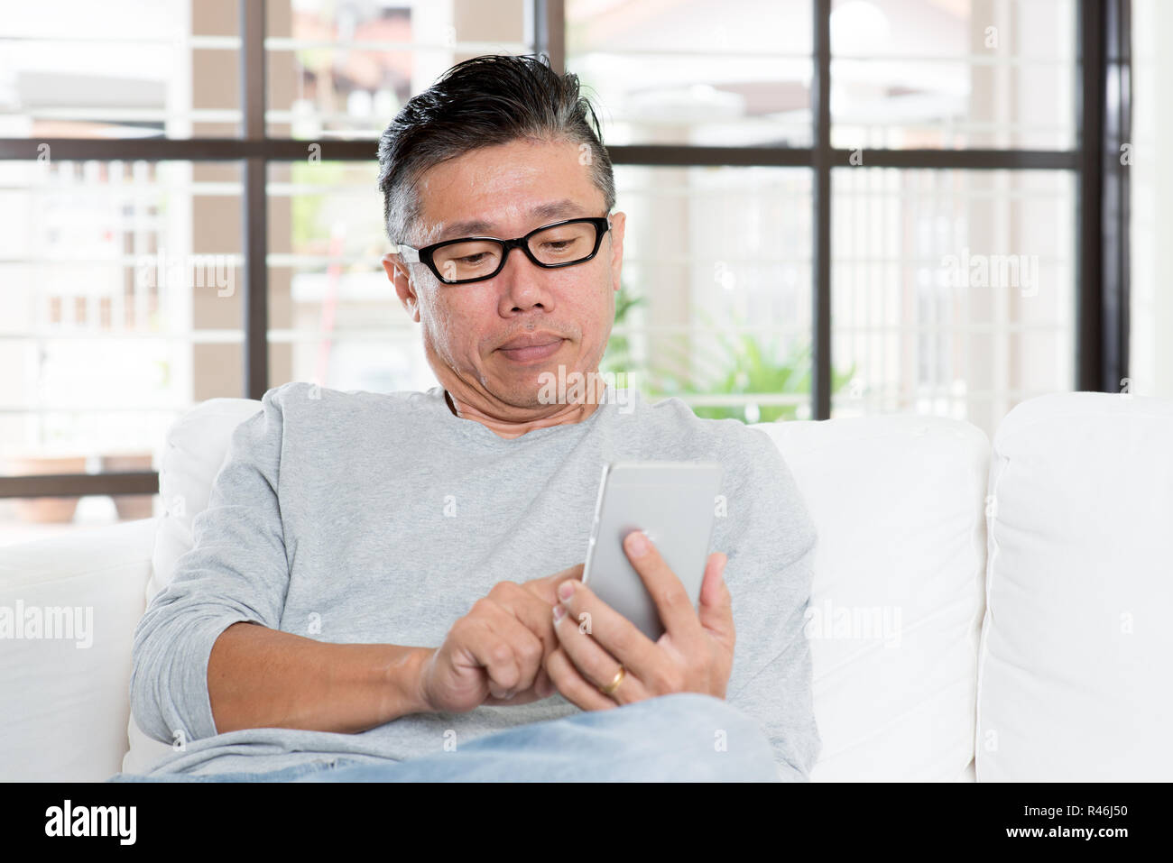 Mature Asian man using smartphone Stock Photo - Alamy