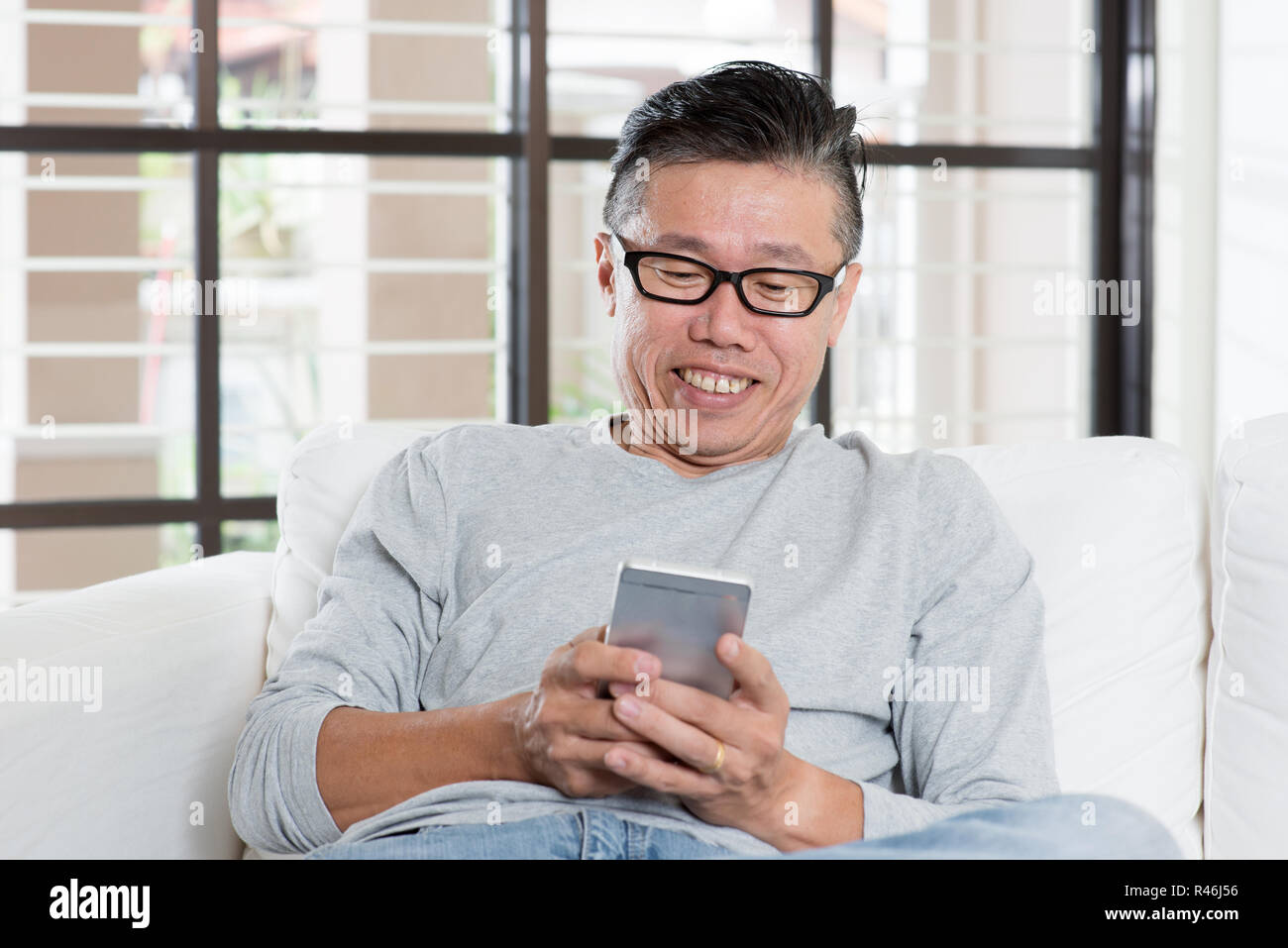 Mature Asian man texting on smartphone Stock Photo - Alamy