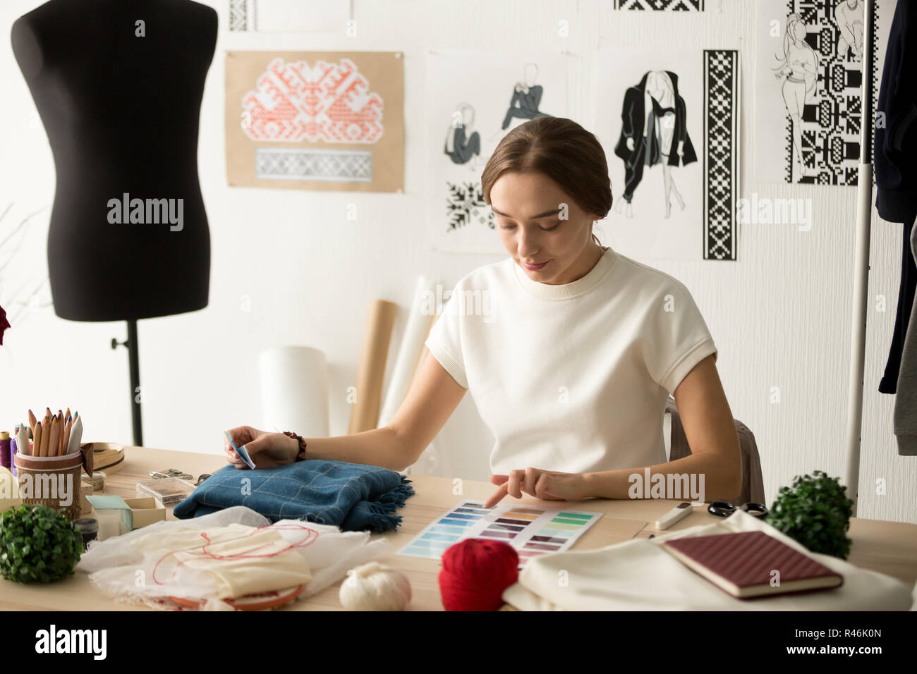 Female clothes designer working with samples in workshop Stock Photo ...