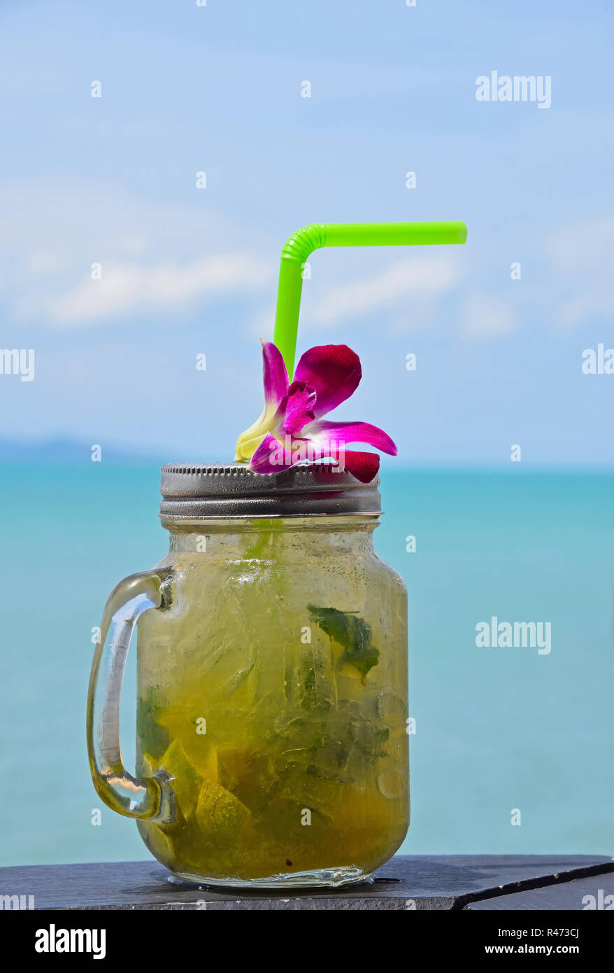Big glass of mojito with orchid flower on beach Stock Photo - Alamy