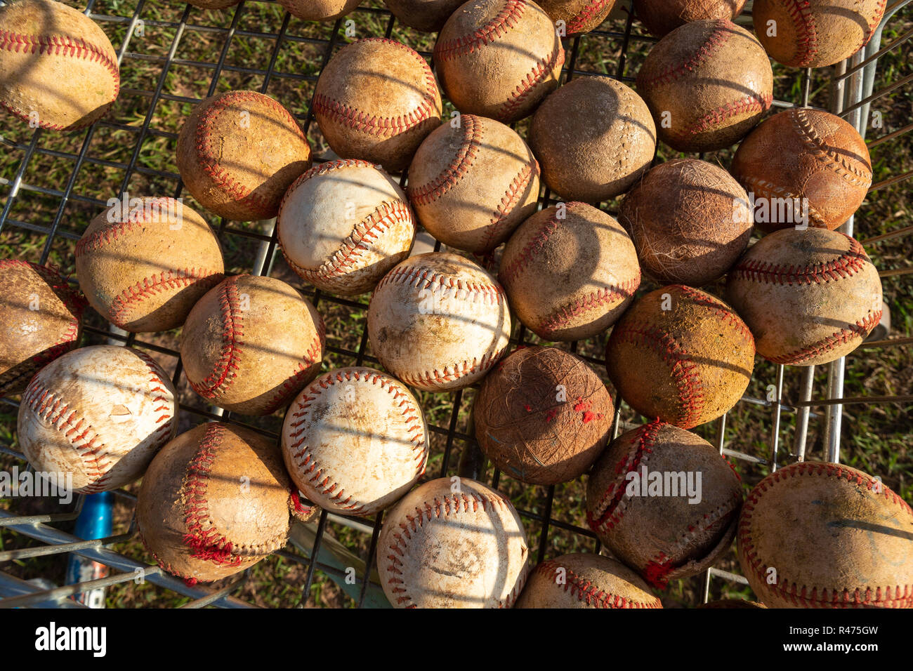 Close up of very used baseball balls in basket with grass background on ...