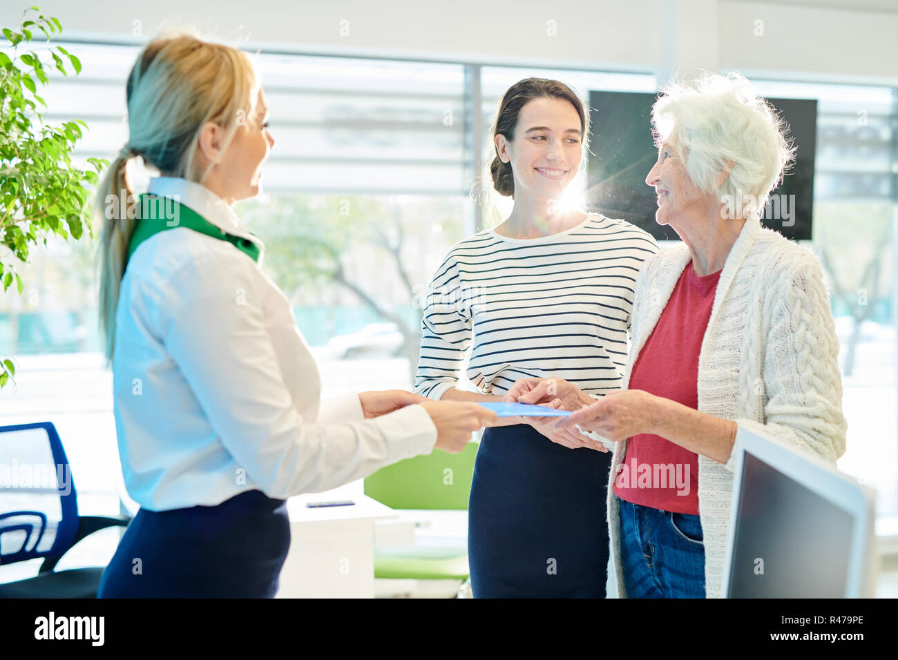 Bank manager giving folder with documents to old lady Stock Photo - Alamy