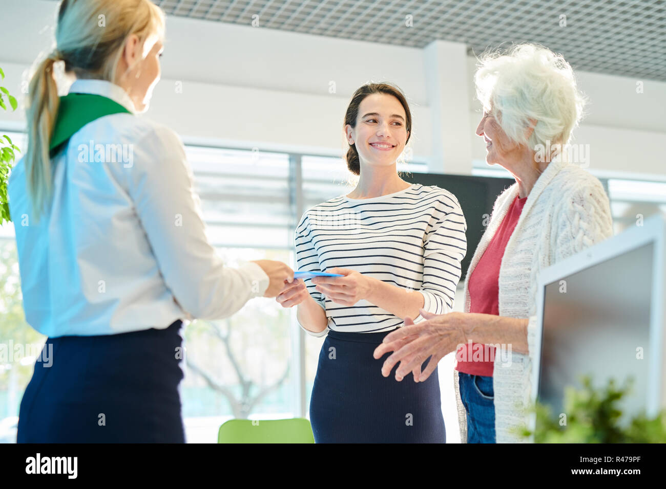 Bank employee issuing documents to young lady with mother Stock Photo ...