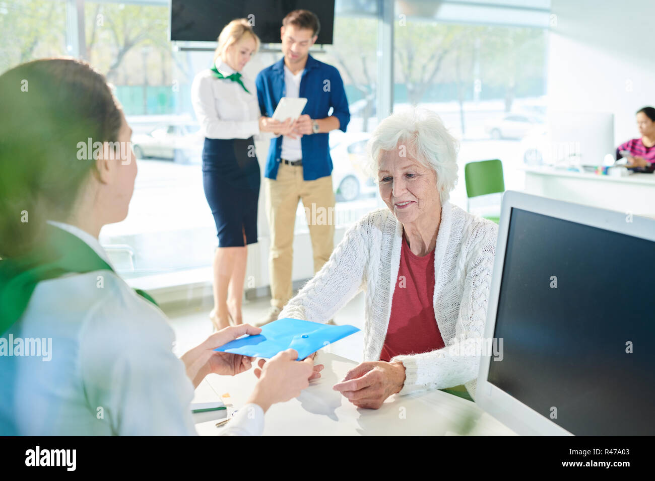 Young woman giving folder hi-res stock photography and images - Alamy