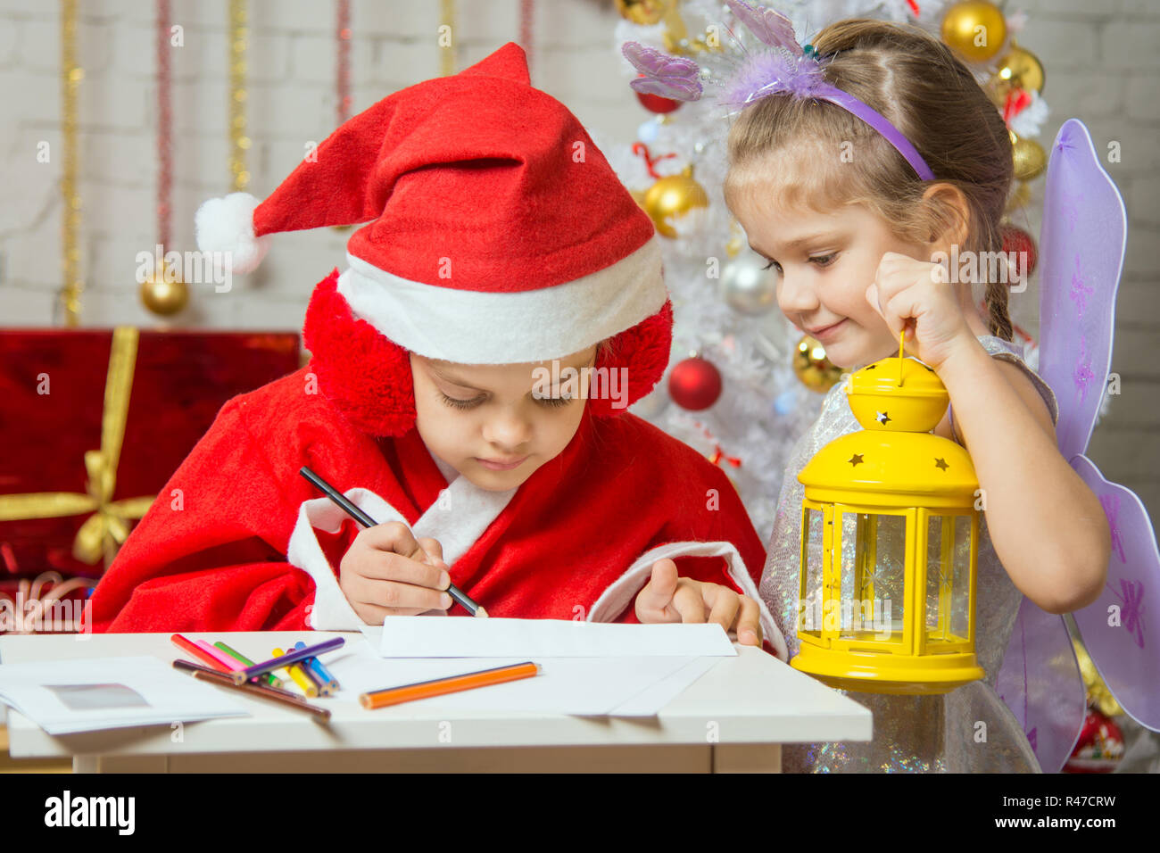Girl dressed as Santa Claus signs the envelope with a letter, standing ...