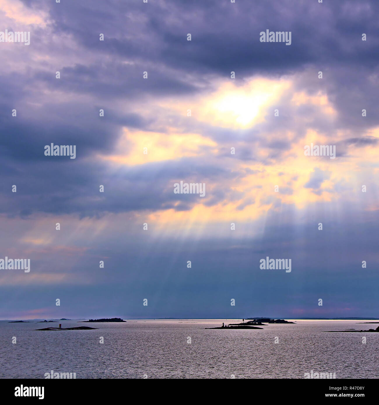 The sun behind the clouds with rays of light shining down on sea Stock ...