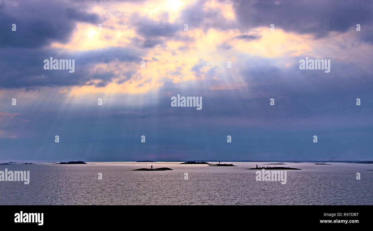 The sun behind the clouds with rays of light shining down on sea Stock ...