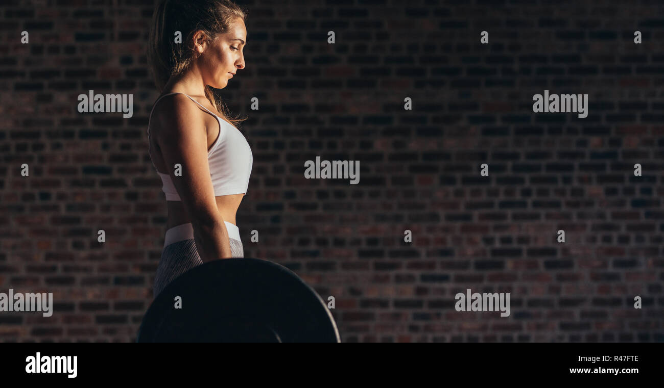 Strong young woman lifting heavy weights at gym. Side view of fit young ...