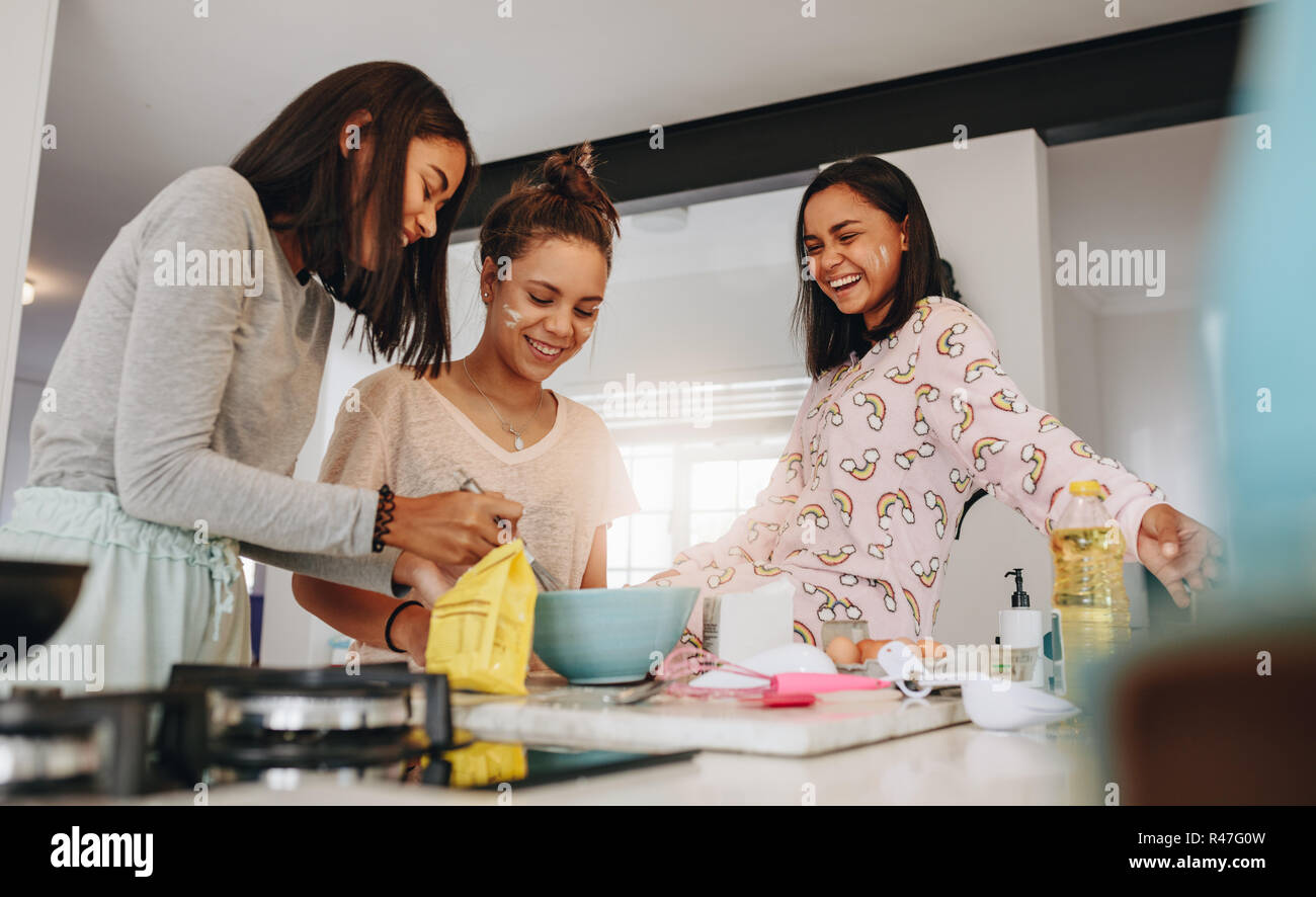 Three girls enjoying making breakfast together in kitchen. Happy girl ...