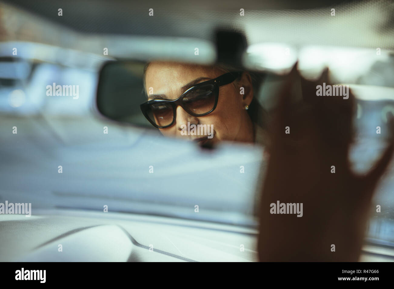 Senior woman driver adjusting rear view car mirror. Reflection in rear ...