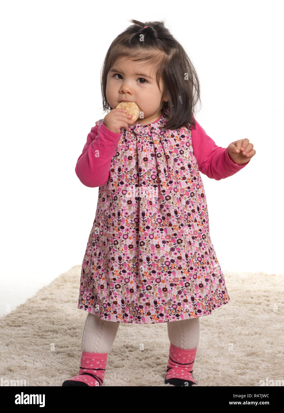 toddler in dress eating a biscuit Stock Photo - Alamy