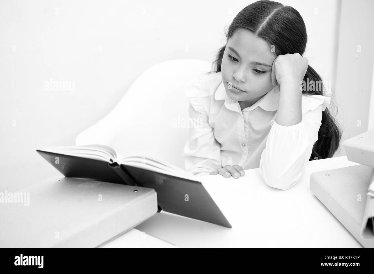 Reading boring book. Girl child reads book while sit table white ...