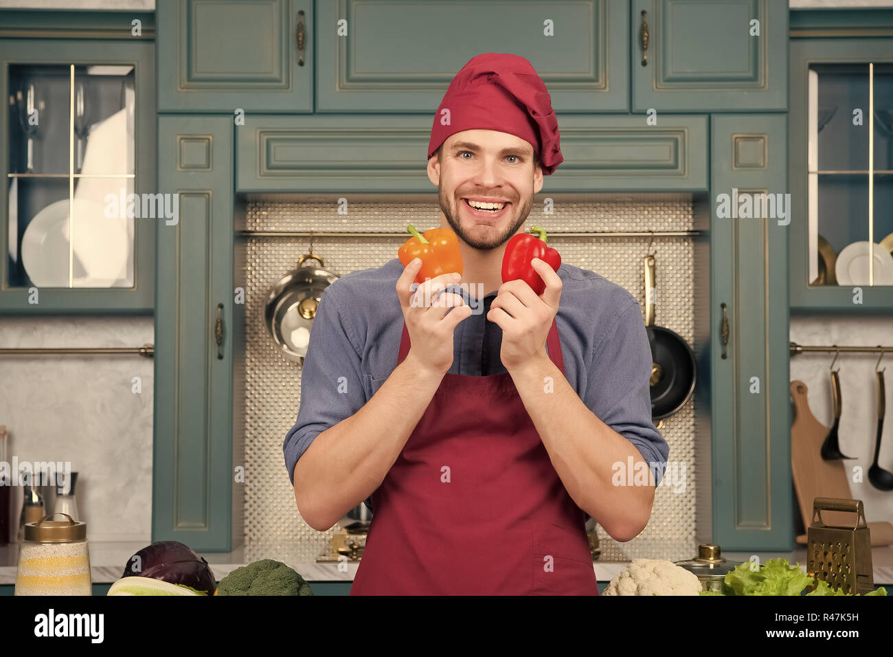 Man in chef hat, apron smile with red and orange pepper vegetable in ...