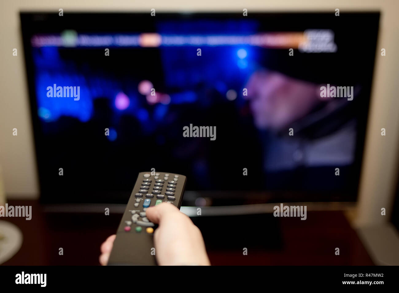 Tv and hand pressing remote control Stock Photo - Alamy