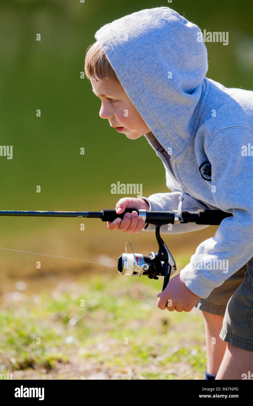 Young boy concentrates while fishing in a pond Stock Photo - Alamy