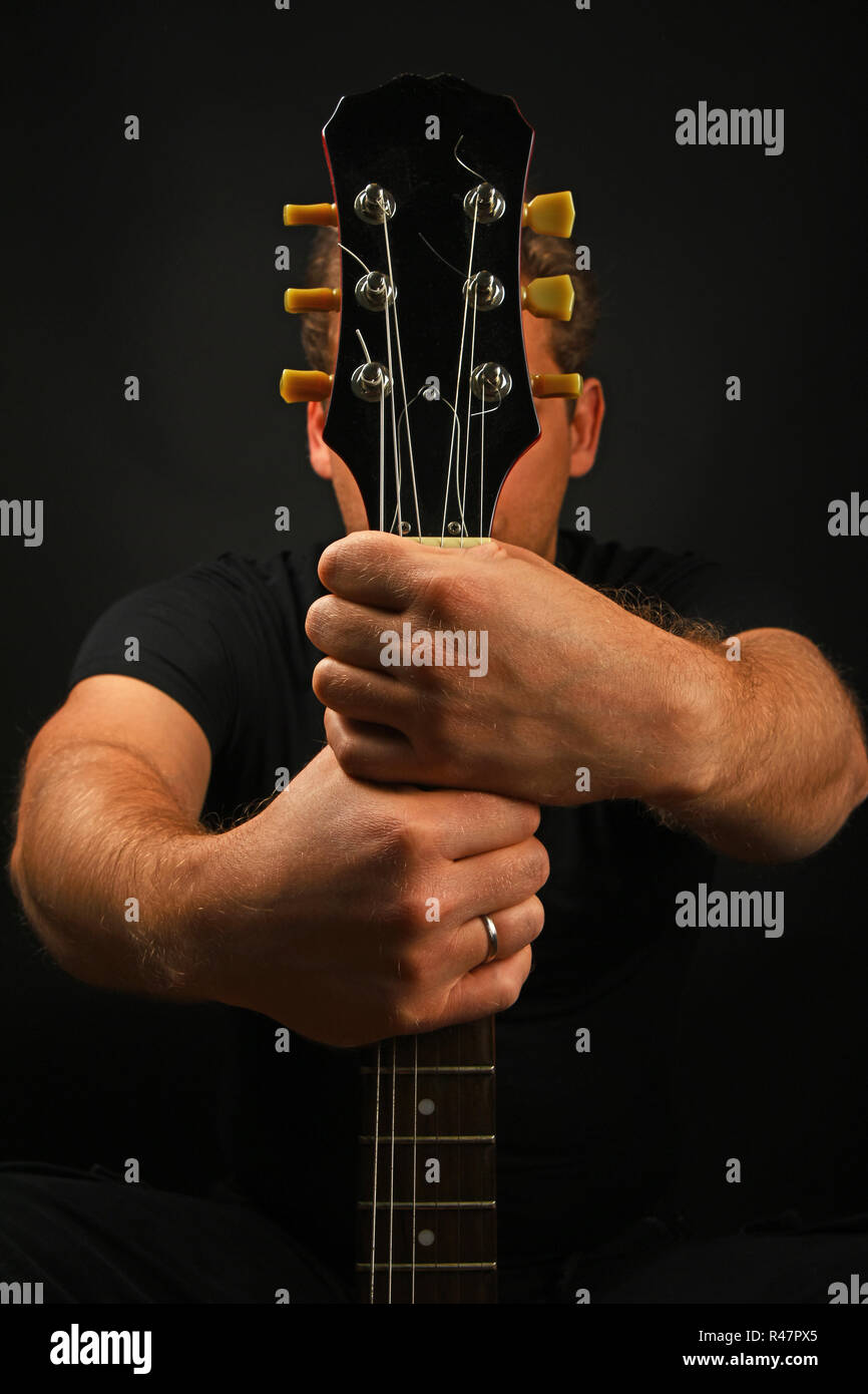 Man holding guitar neck with two hands isolated on black Stock Photo ...