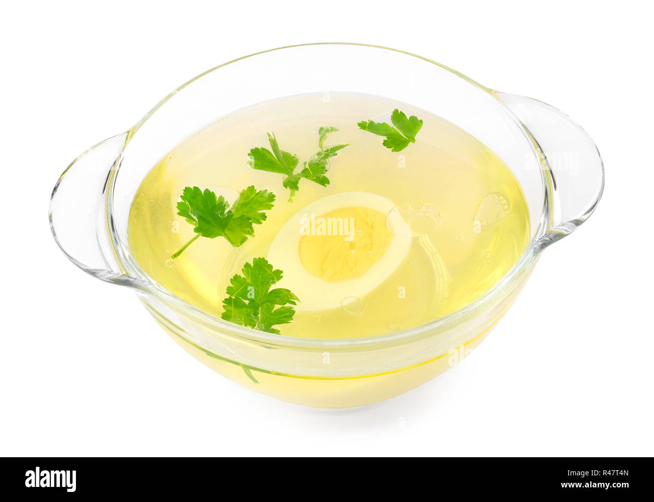 Low-fat chicken broth with a half cooked egg and parsley in a glass ...