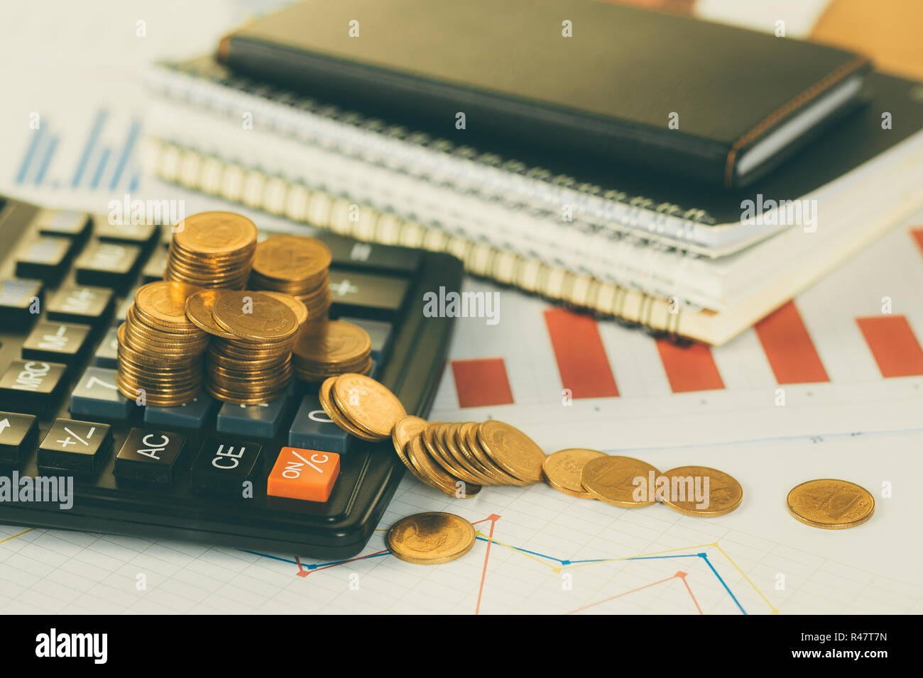 Coin stack and financial graph paper sheet with calculator on working ...