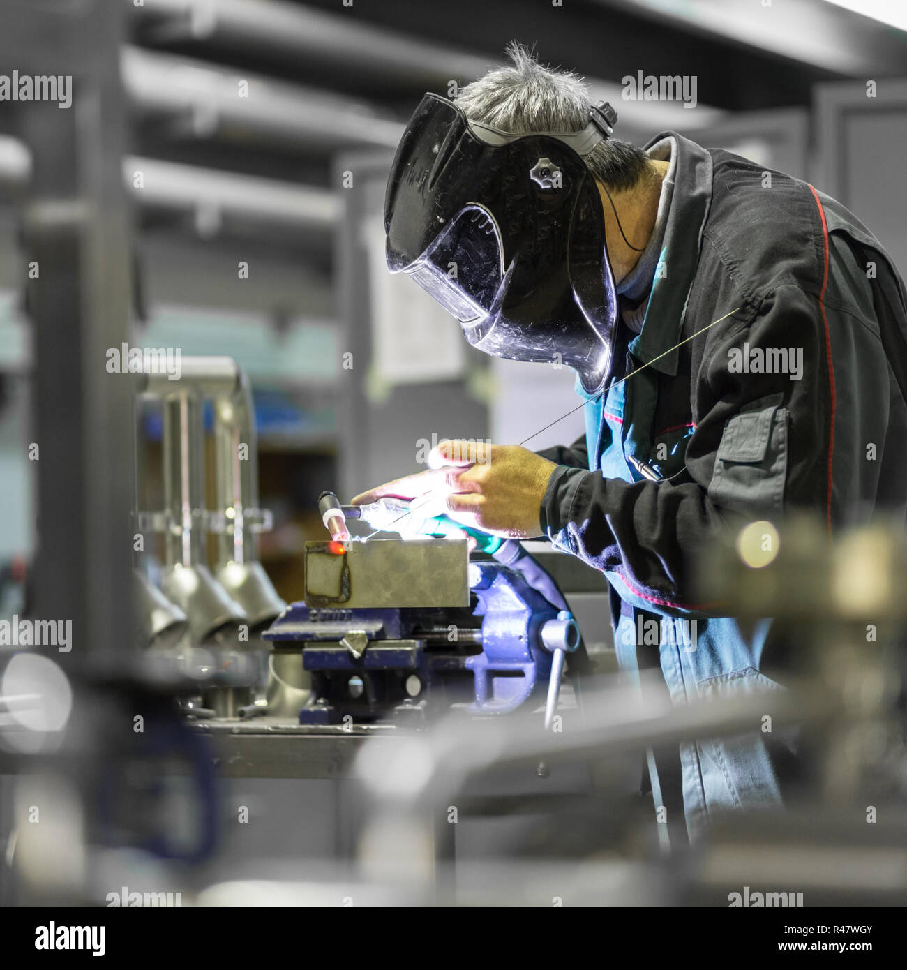 Industrial worker welding in metal factory Stock Photo - Alamy