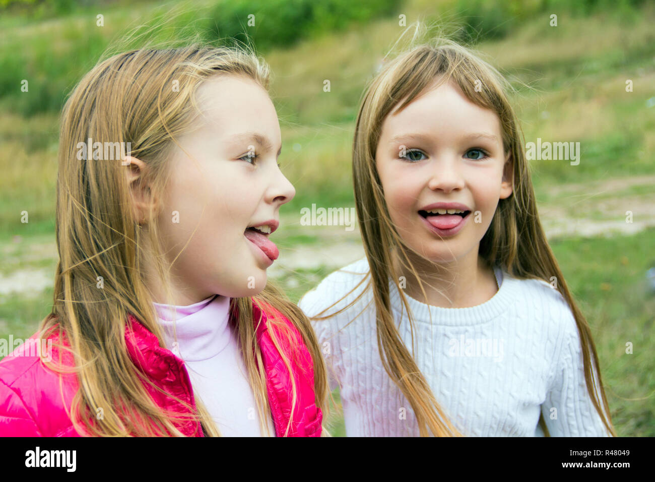 Cute two playing girls put out tongues Stock Photo - Alamy