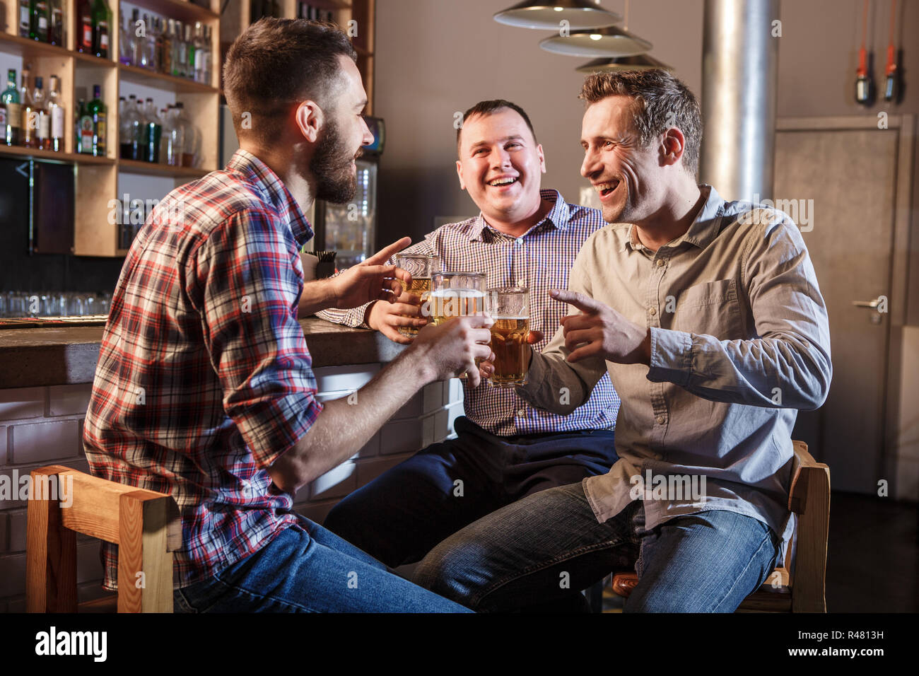 Happy friends drinking beer at counter in pub Stock Photo - Alamy