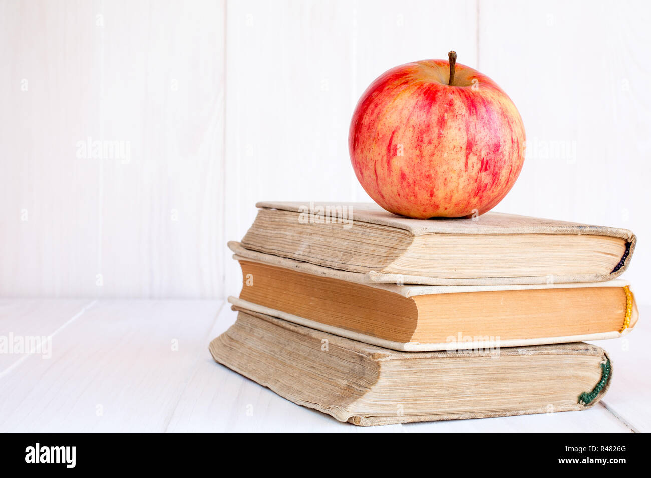 Three old books with red apple Stock Photo - Alamy