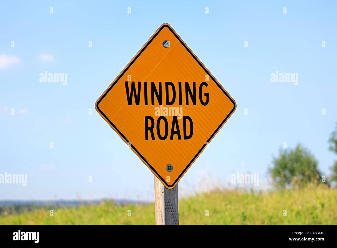 A winding road sign against a blue sky Stock Photo - Alamy