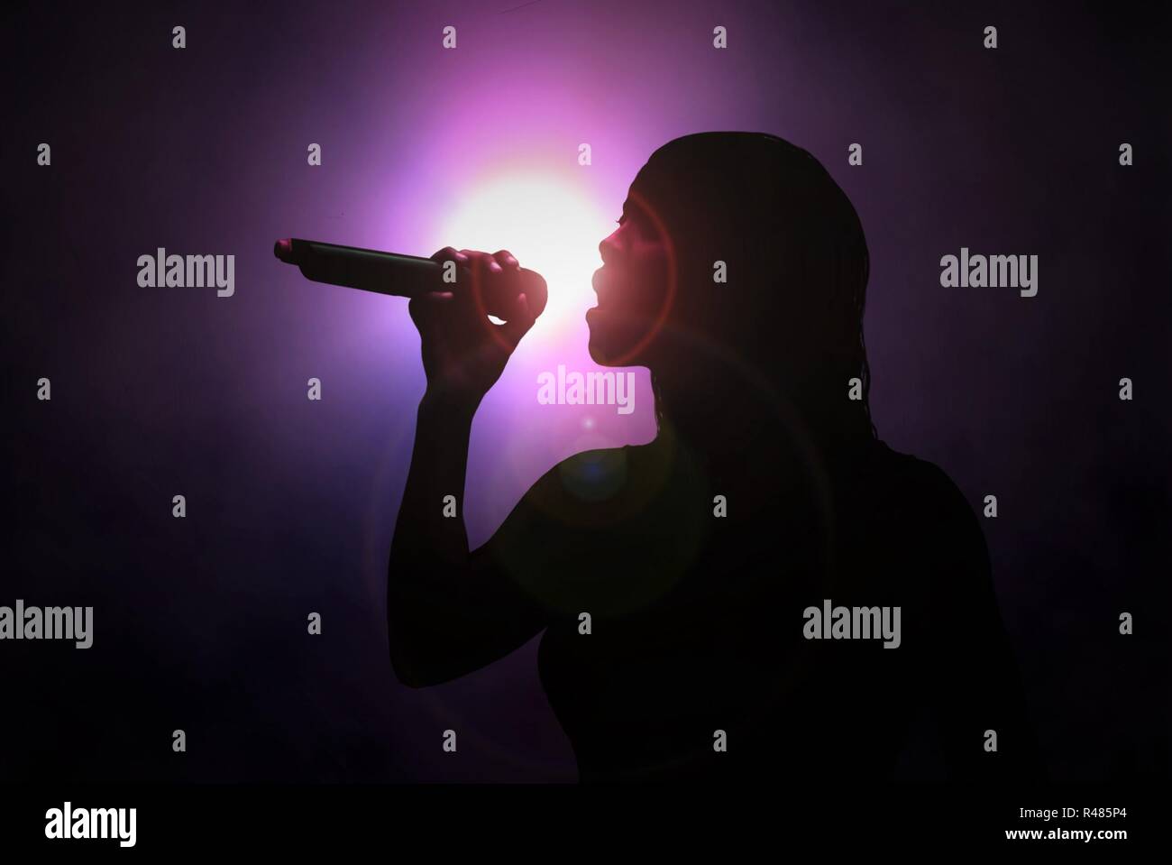 Women singing with microphone under spotlight Stock Photo - Alamy