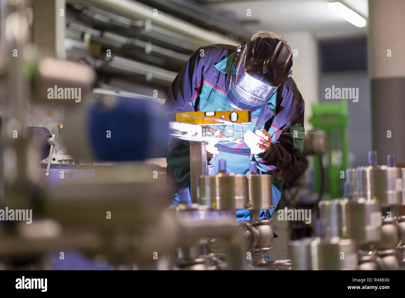 Industrial worker welding in metal factory Stock Photo - Alamy