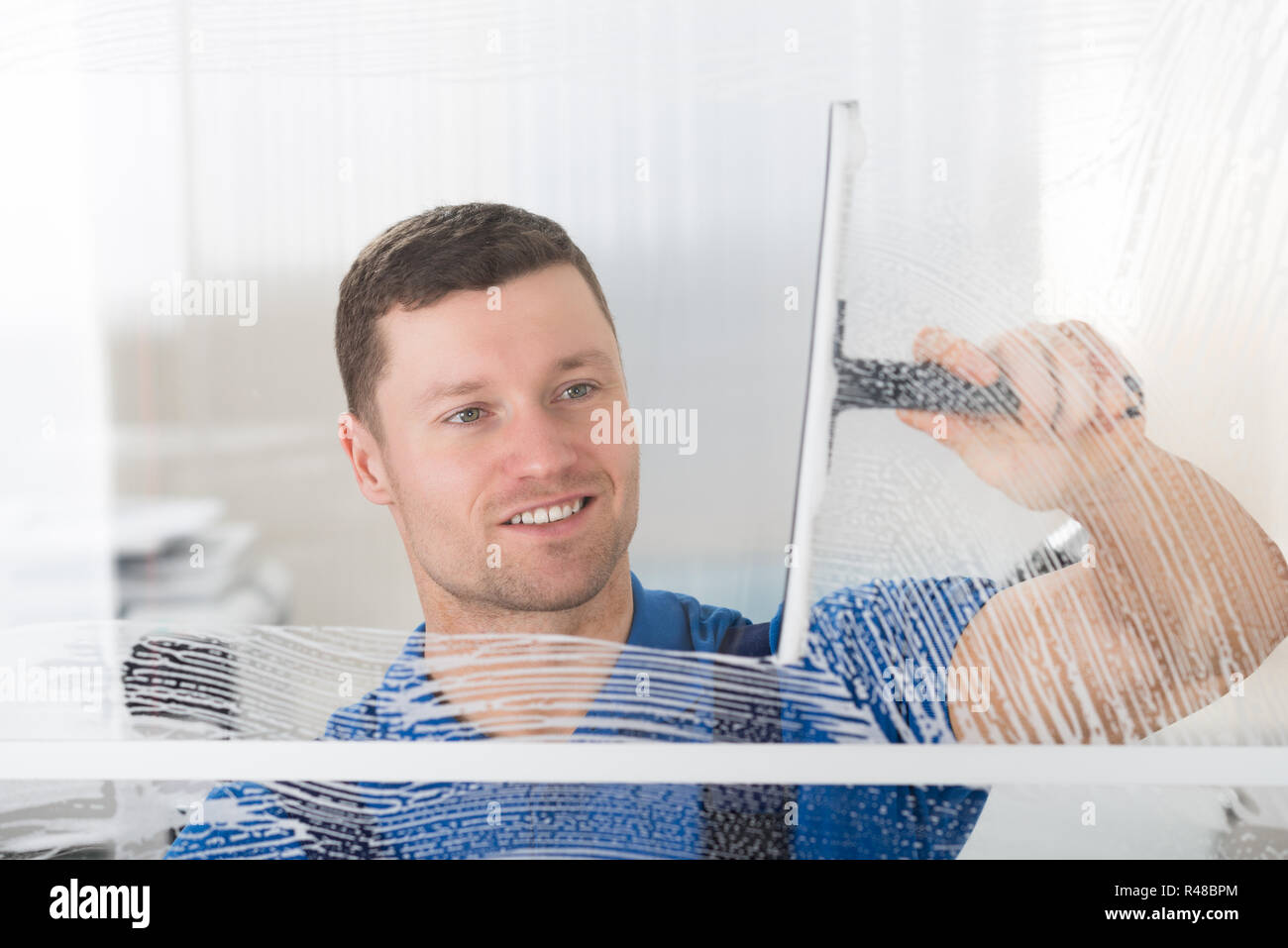 Worker Cleaning Soap Sud On Window With Squeegee Stock Photo - Alamy