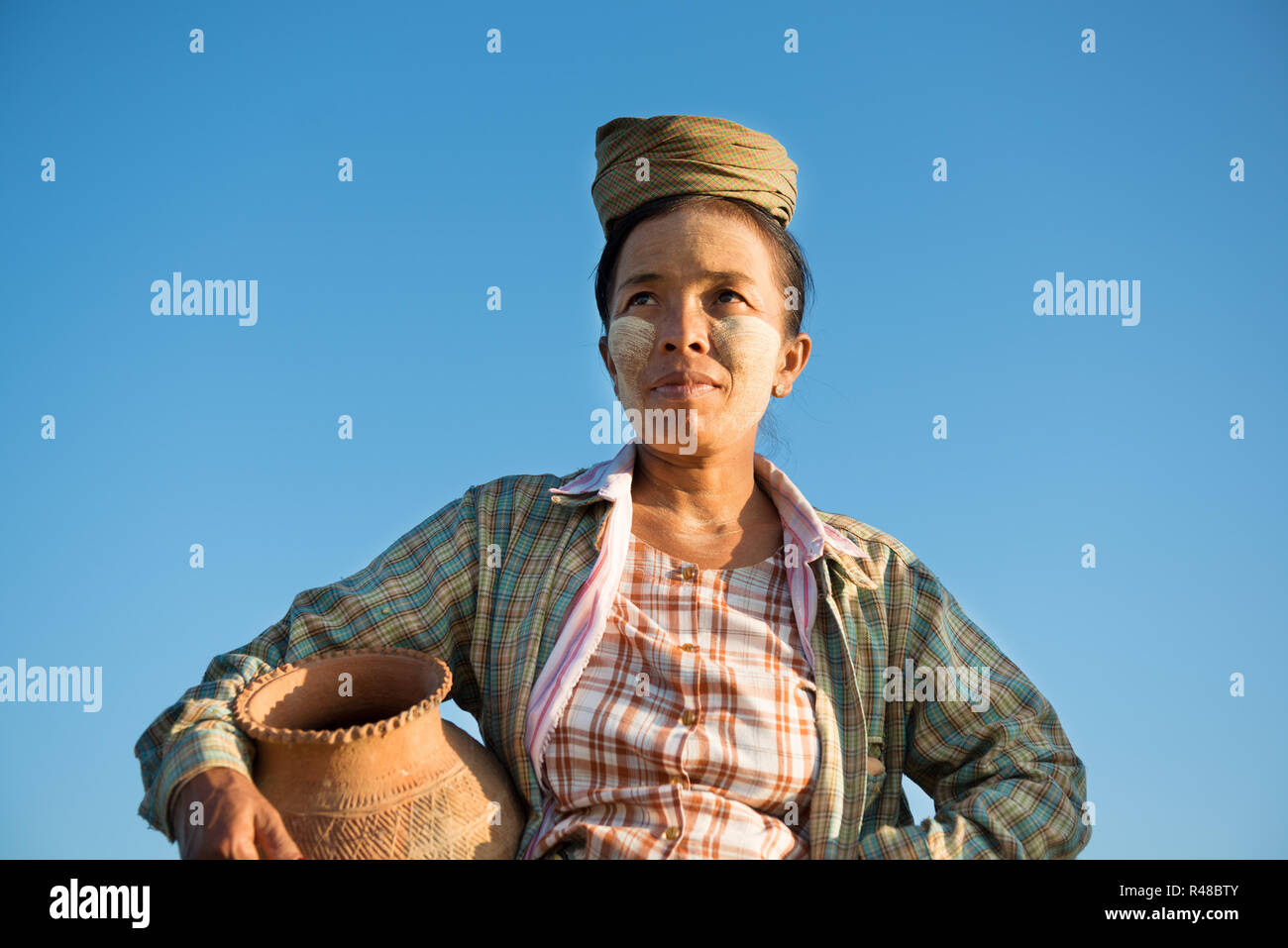 Mature Asian traditional female farmer carrying clay pot Stock Photo ...