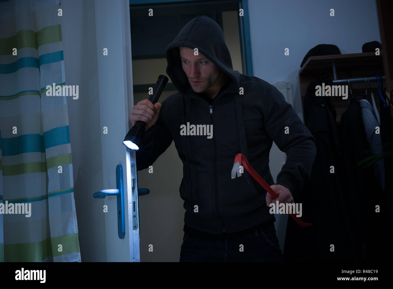 Robber With Crowbar And Flashlight Entering In House Stock Photo - Alamy