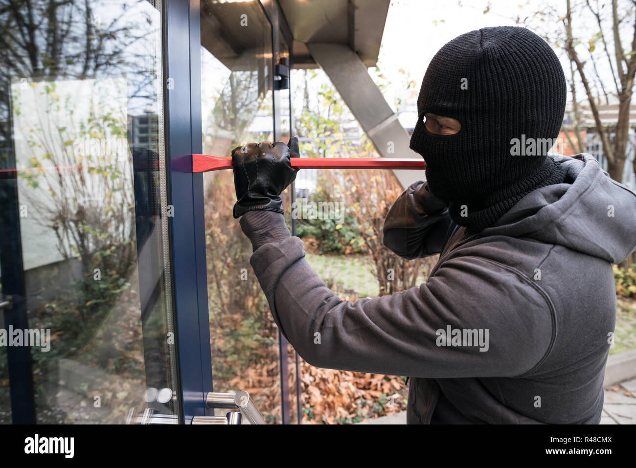 Man Using Crowbar To Open Glass Door Stock Photo - Alamy