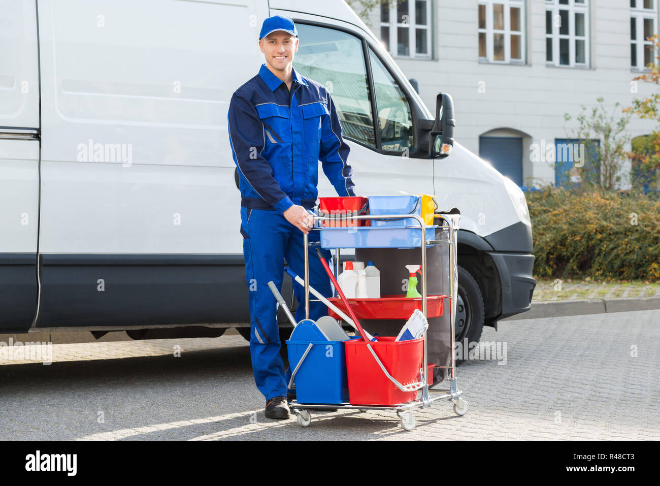 Happy Janitor Standing With Cleaning Equipment Stock Photo - Alamy