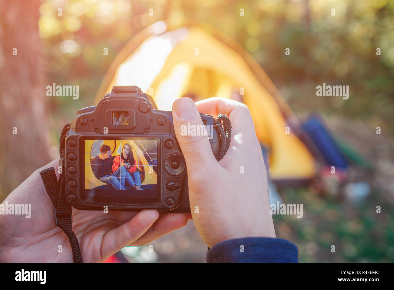Man holding camera that take picture of couple. They sit in tent ...