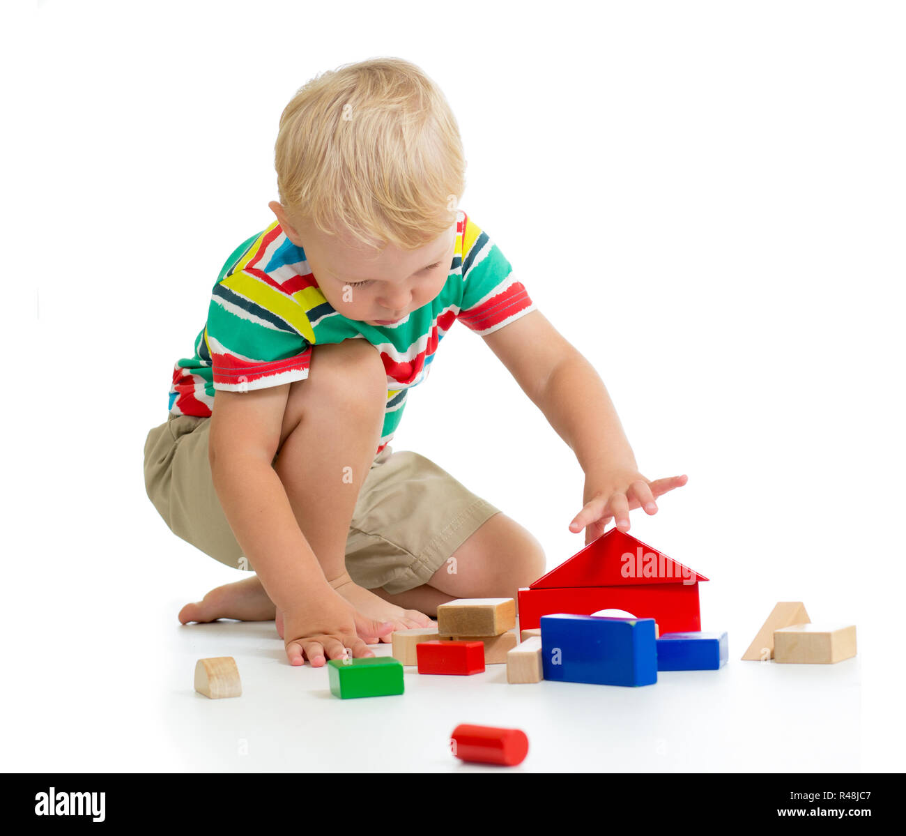 Child boy building castle with colorful wooden cubes, isolated on white ...