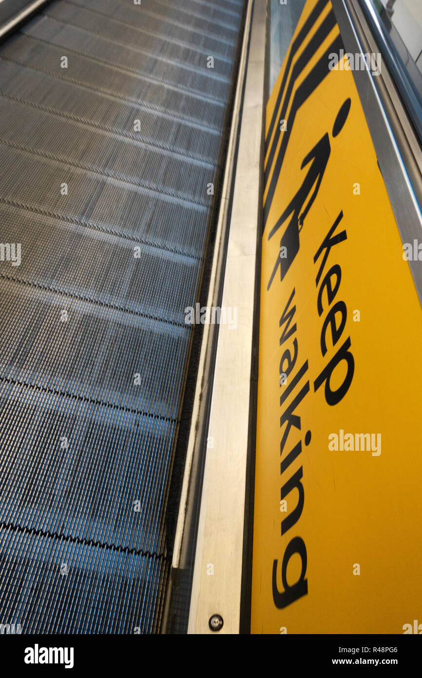 Keep Walking yellow walking man sign next to flat escalator airport ...