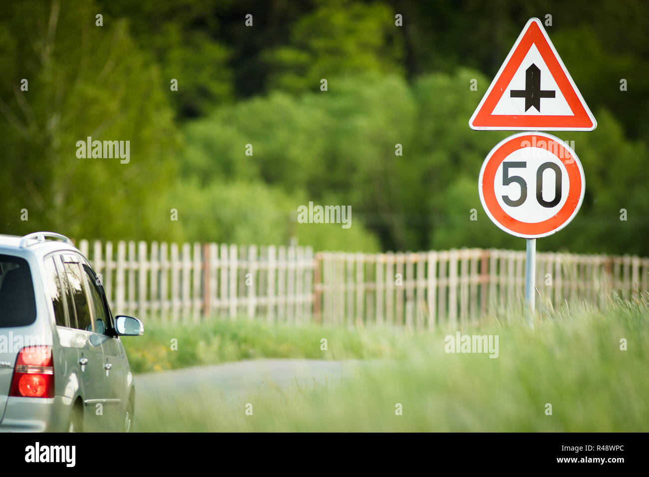 Car on a country road with limited speed and crossroad sign Stock Photo ...