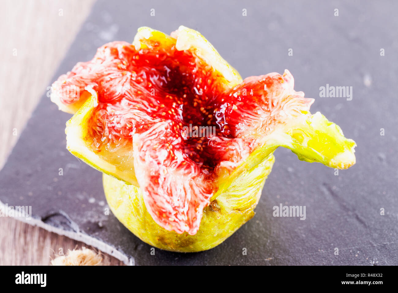 Open fig over black stone Stock Photo - Alamy