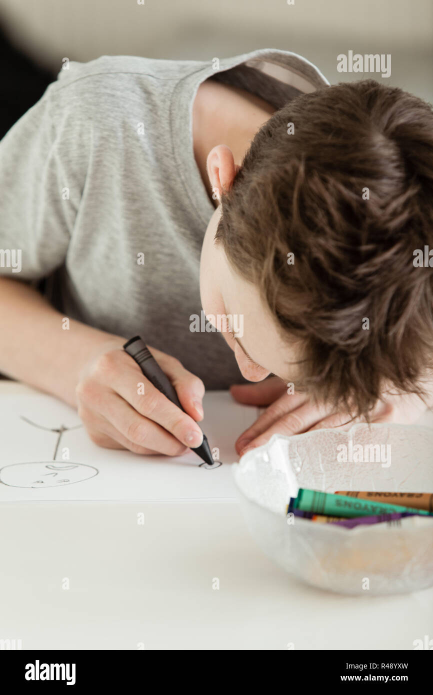 Boy carefully drawing with crayon on paper Stock Photo - Alamy