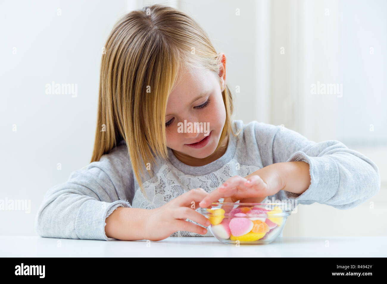Beautiful child eating sweets at home Stock Photo - Alamy