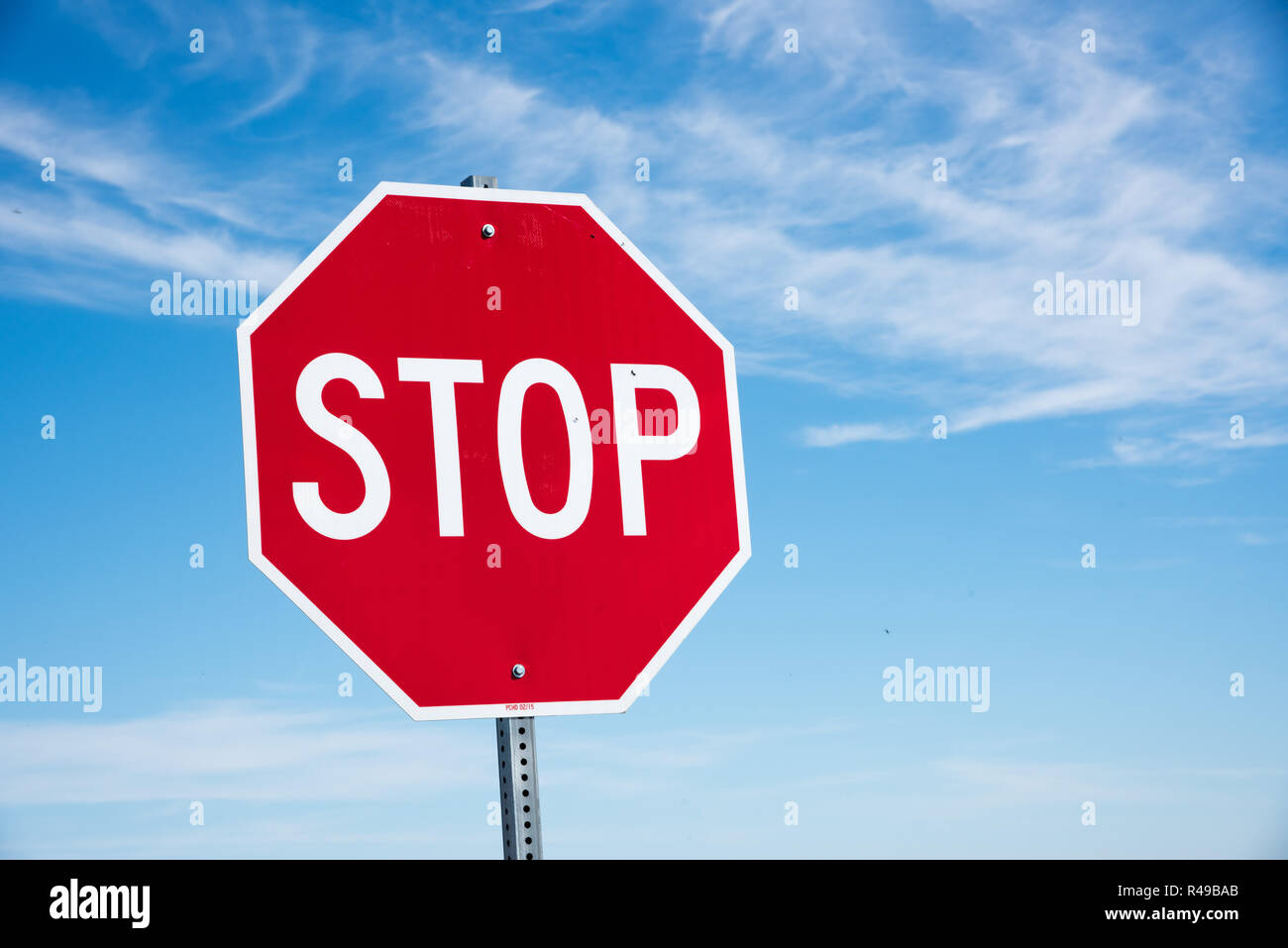 Low angle view of red and white stop sign under a blue sky with clouds ...